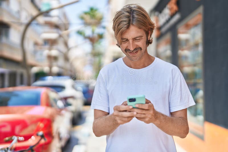 Young Blond Man Smiling Confident Using Smartphone at Street Stock ...