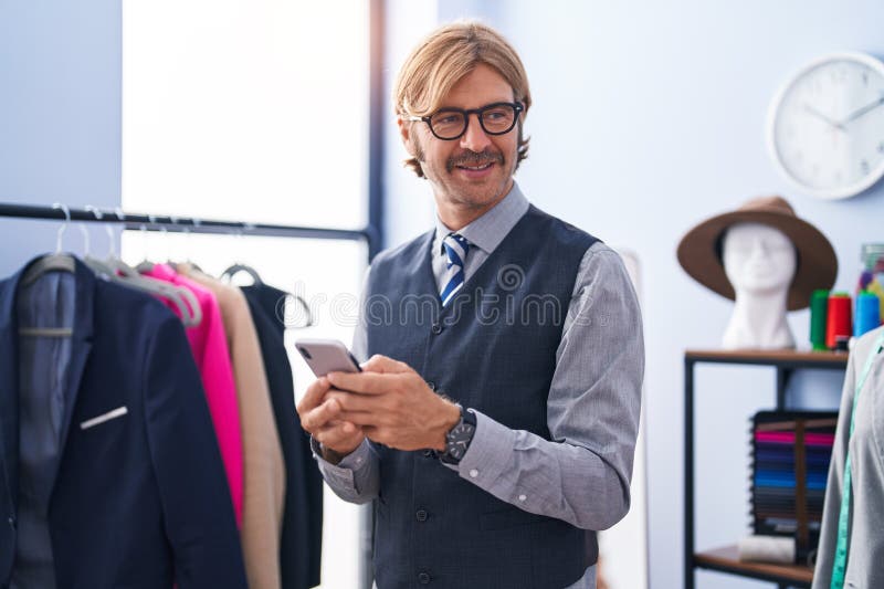 Young Blond Man Tailor Smiling Confident Using Smartphone at Clothing ...