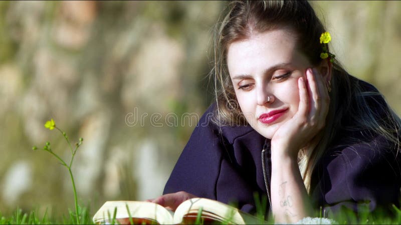 Young Blond Woman is Relax and Reading Book on Grass in Nature Stock ...