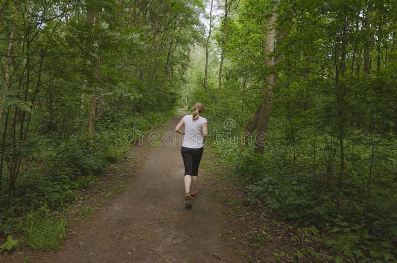 Young Blond Woman Running in a Forest Stock Photo - Image of activity ...