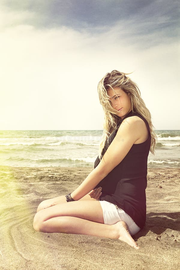 Young Blonde Girl Relaxing On The Beach Sand Wind In Her Blonde Hair