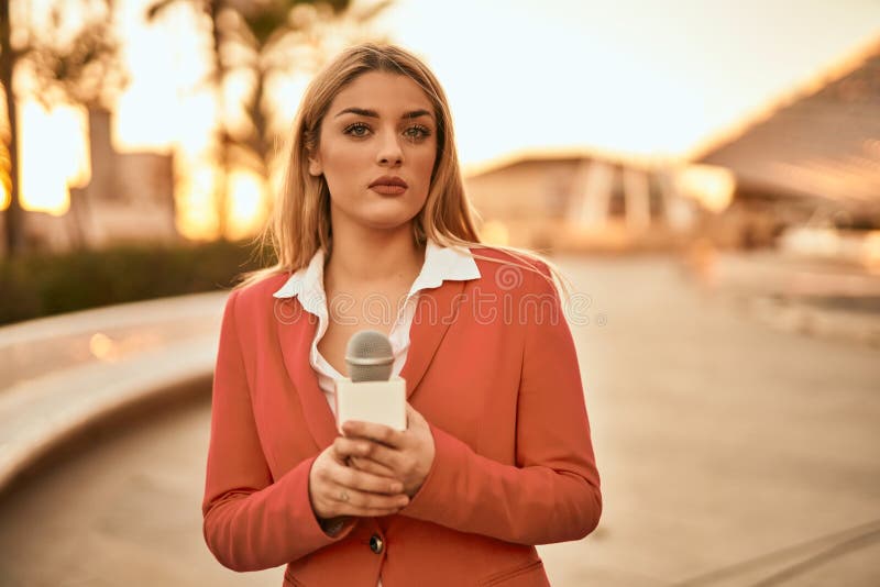 Young Blonde Reporter Woman Working Using Microphone at the City Stock ...
