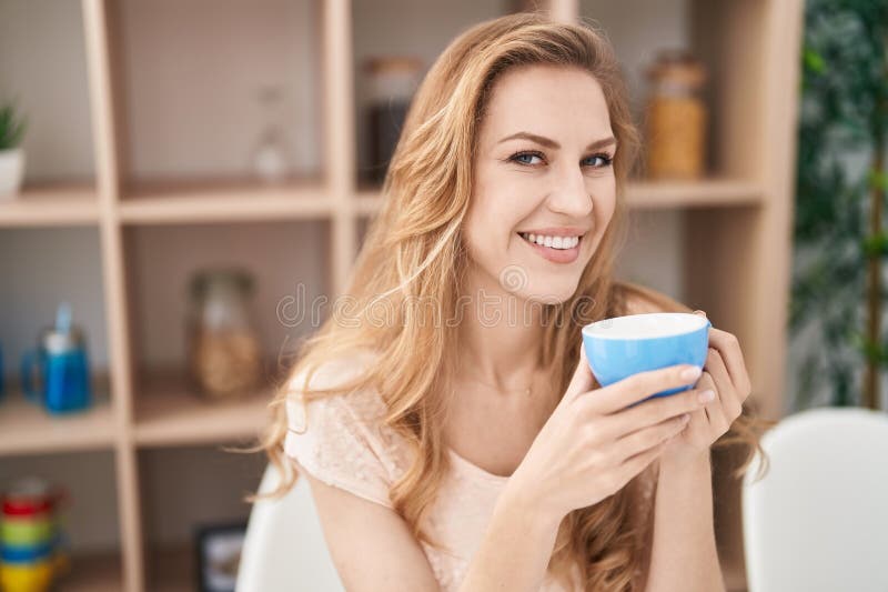 Young Blonde Woman Drinking Coffee Sitting on Table at Home Stock Image ...