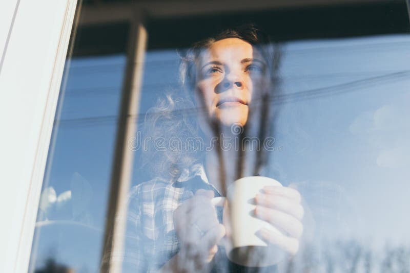 Young Blonde Woman Looking Out of the Window with a Concerned ...