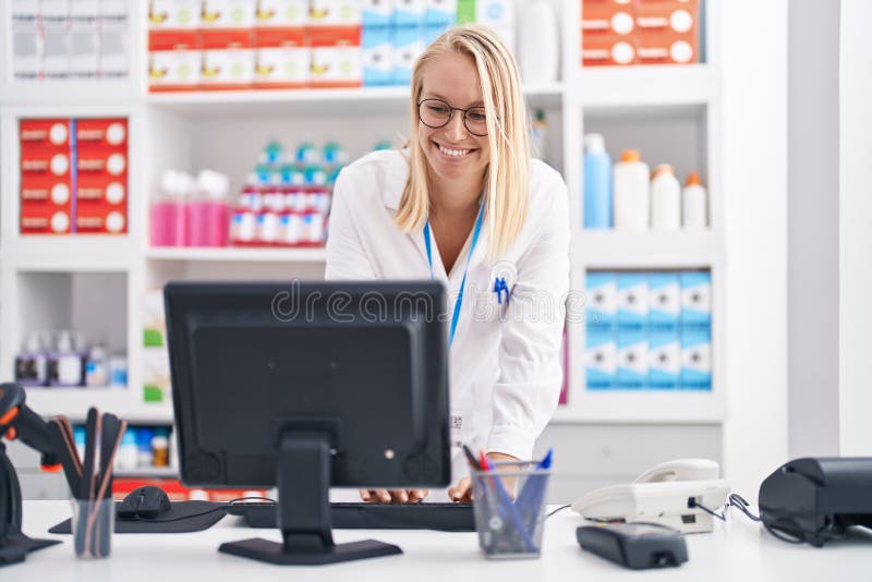 Young Blonde Woman Pharmacist Using Computer Working at Pharmacy Stock ...