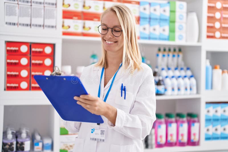 Young Blonde Woman Pharmacist Writing on Document at Pharmacy Stock ...