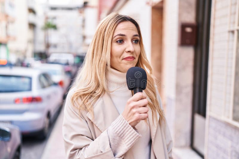 Young Blonde Woman Reporter Working Using Microphone at Street Stock ...