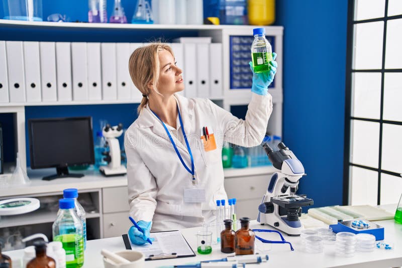 Young Blonde Woman Scientist Measuring Liquid Writing on Document at ...