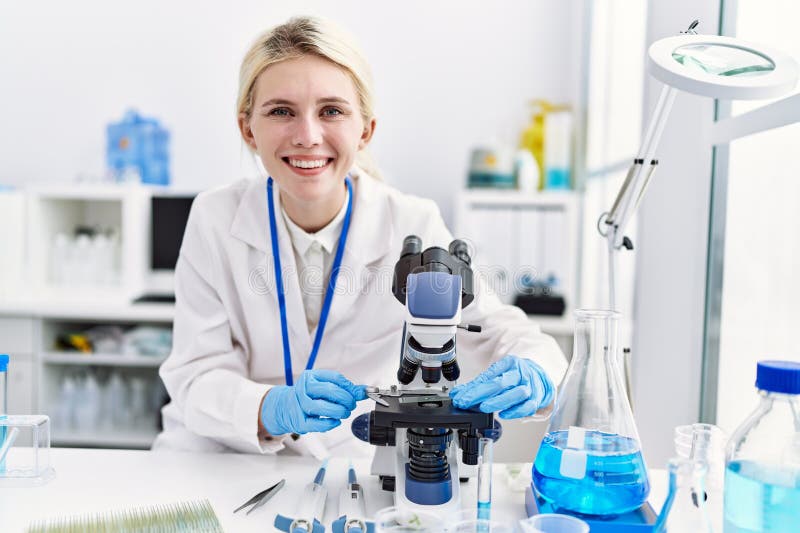 Young Blonde Woman Scientist Using Microscope Smiling at Laboratory ...