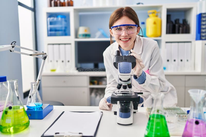 Young Blonde Woman Scientist Using Microscope Smiling at Laboratory ...