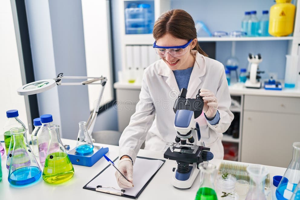 Young Blonde Woman Scientist Using Microscope Writing on Document at ...