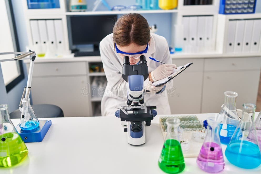 Young Blonde Woman Scientist Using Microscope Writing on Document at ...