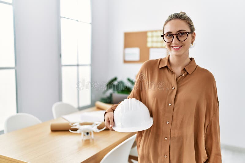 Young Blonde Woman Smiling Confident Holding Architect Helmet at ... Young Blonde Woman Smiling Confident Holding Architect Helmet at ...