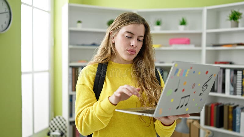 Young Blonde Woman Student Wearing Backpack Using Laptop at Library ...