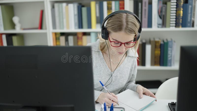 Young Blonde Woman Using Computer Taking Notes at Library University ...
