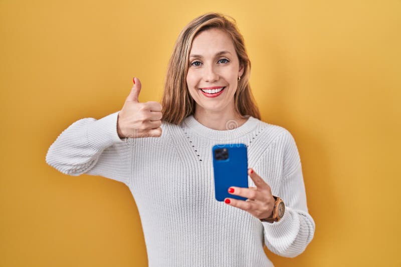 Young Blonde Woman Using Smartphone Typing Message Doing Happy Thumbs ...