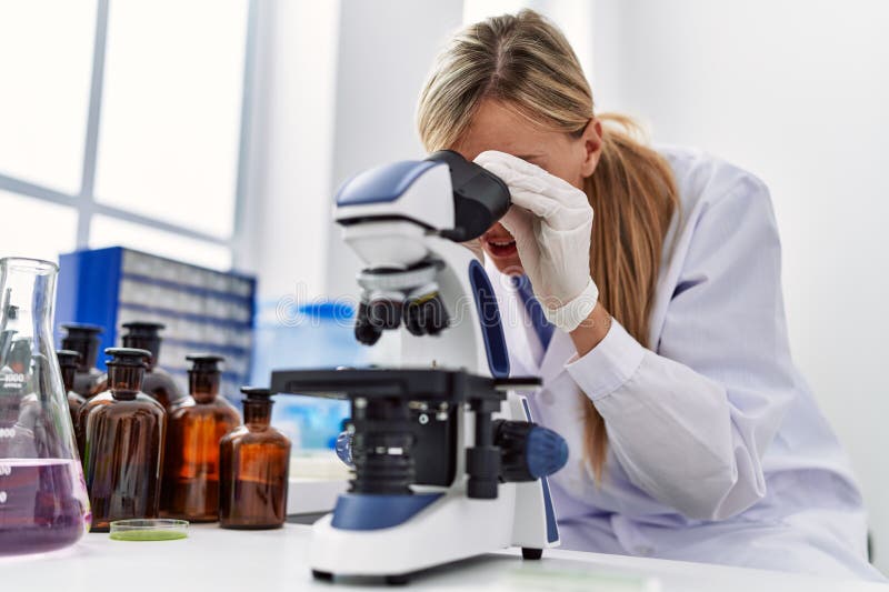 Young Blonde Woman Wearing Scientist Uniform Using Microscope at ...