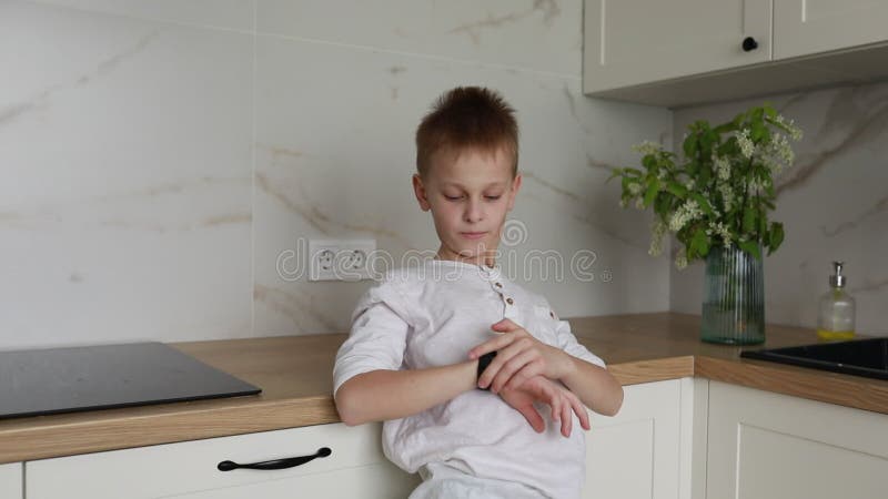 Young Boy Checking Smartwatch in Bright Kitchen during Morning Routine ...