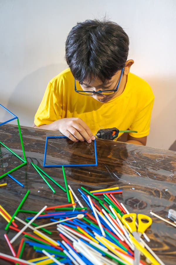A Young Boy is Constructing Colorful Plastic Sticks with Glue Gun. Fun ...