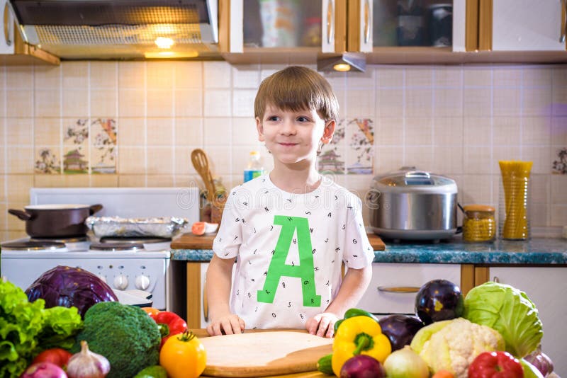 The Young Boy in Cooking Standing in the Kitchen Near Table with Stock ...