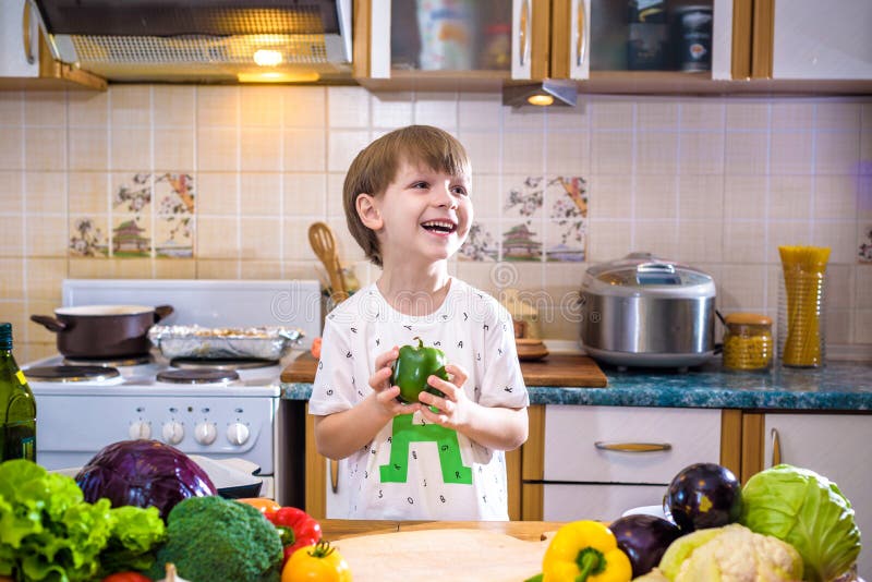The Young Boy in Cooking Standing in the Kitchen Near Table with Stock ...