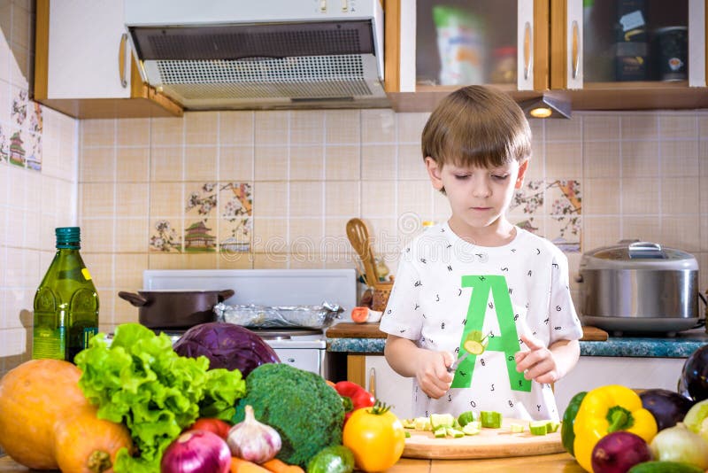 The Young Boy in Cooking Standing in the Kitchen Near Table with Stock ...