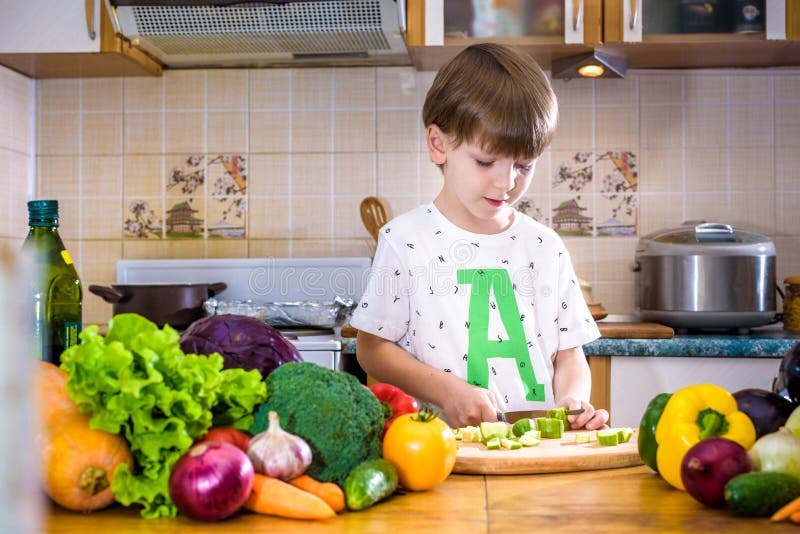 The Young Boy in Cooking Standing in the Kitchen Near Table with Stock ...
