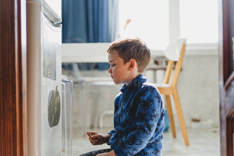 A Young Boy Drawing on the Refrigerator with a Marker Stock Photo ...