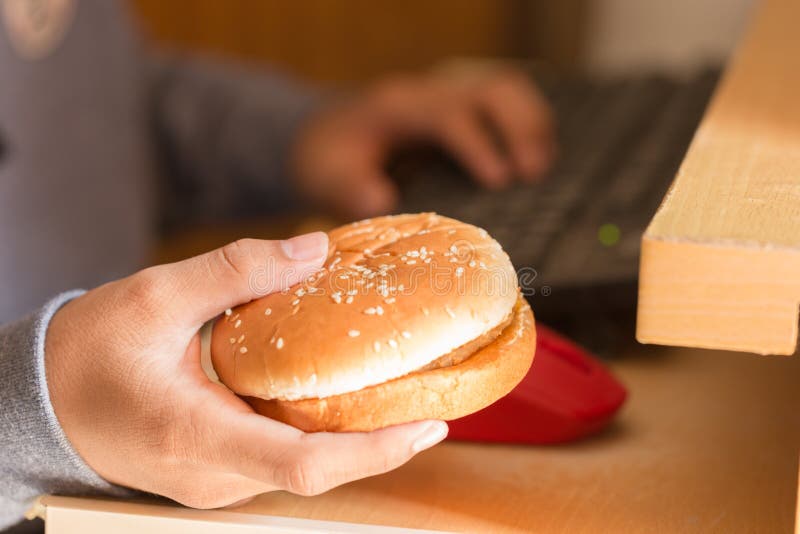 Young Boy Eating Burger and Using Computer Stock Photo - Image of wood ...