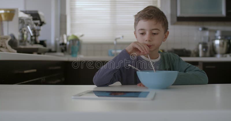 Young Boy Engages with Digital Tablet while Eating Breakfast at Kitchen ...