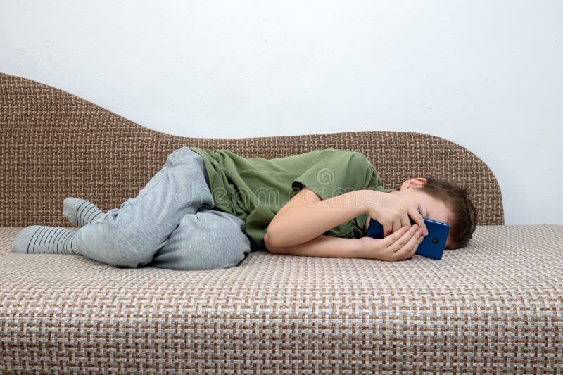 A Young Boy, Engrossed in a Digital Device, Sits Comfortably on the ...