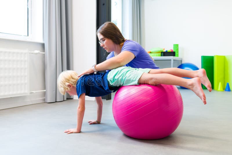 Young Boy with Female Physical Therapist Exercising Using Ball during ...