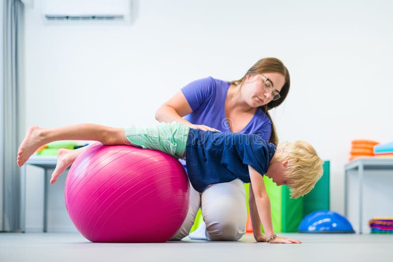 Young Boy with Female Physical Therapist Exercising Using Ball during ...