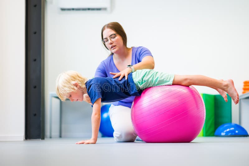 Young Boy with Female Physical Therapist Exercising Using Ball during ...