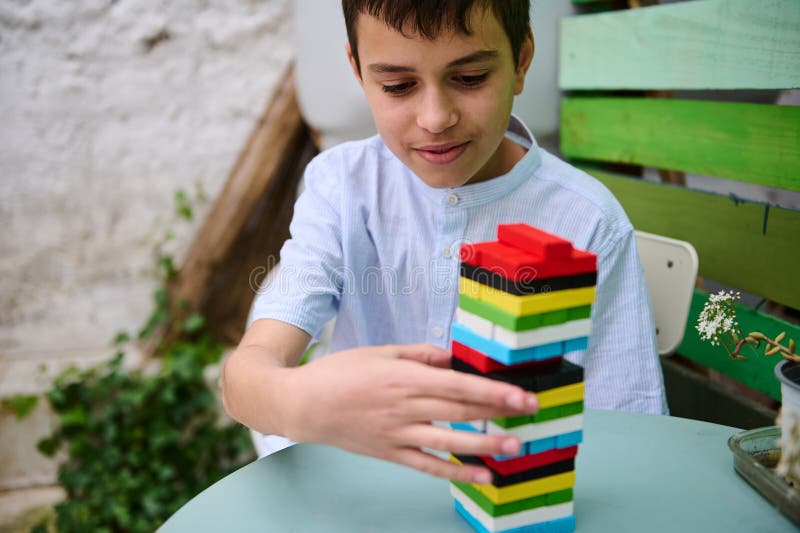 Young Boy Focused on Playing with Colorful Stackable Blocks Outdoors ...