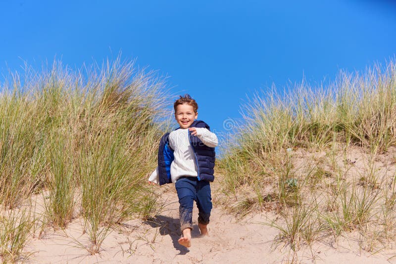 Young Boy Having Fun on Beach Vacation Running Down Sand Dunes Stock ...