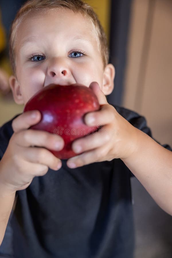 A Young Boy is Holding a Red Apple in His Hand Stock Photo - Image of ...