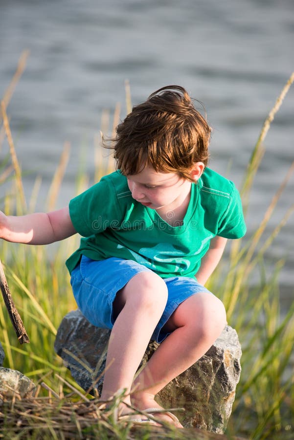 Young Boy Holding Stick from among the Reeds Along the Bay Stock Photo ...