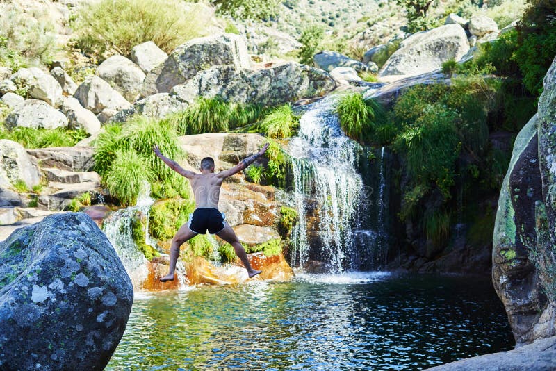 Young Boy Jumps into the Water of the Natural Pool with Waterfall Stock ...