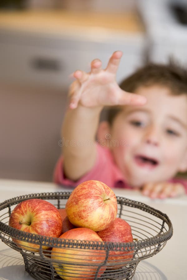 Young Boy in Kitchen Getting Apple Off Counter Stock Photo - Image of ...