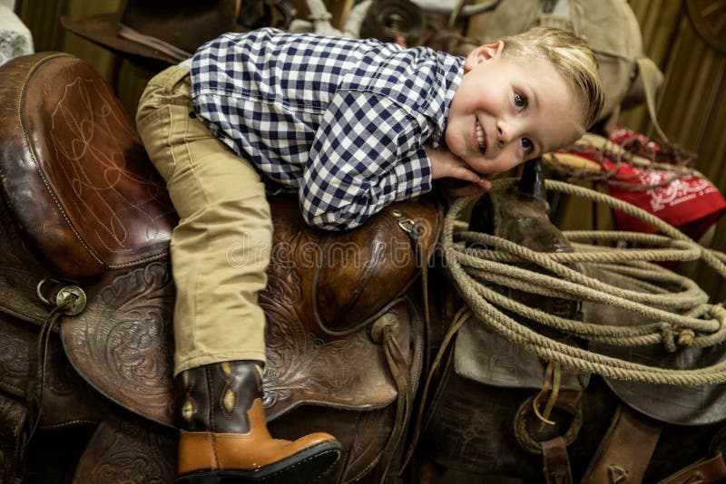 Young Boy Laying on a Western Cowboy Saddle Smiling Stock Image - Image ...