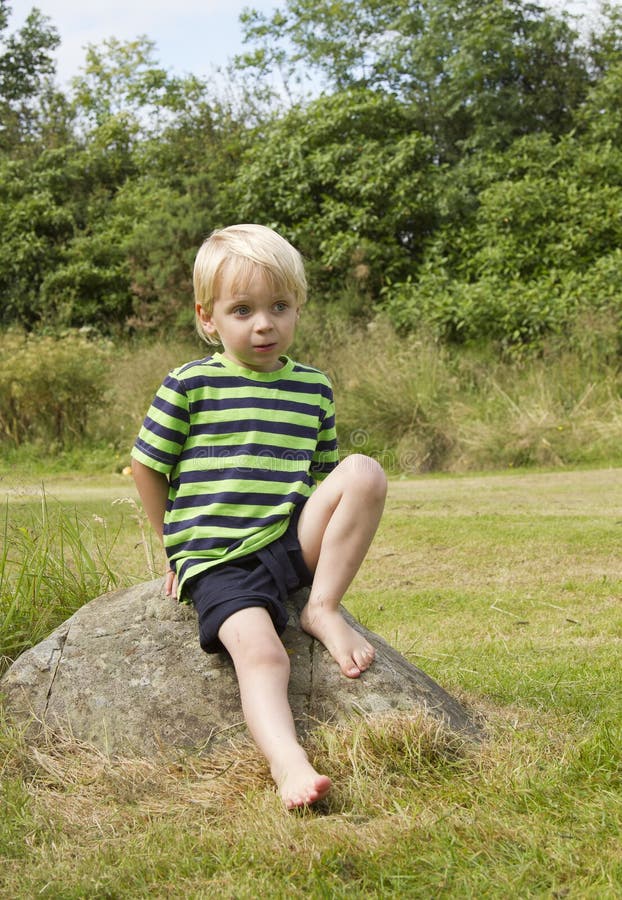 Young boy posing on a rock stock image. Image of hand - 26050425