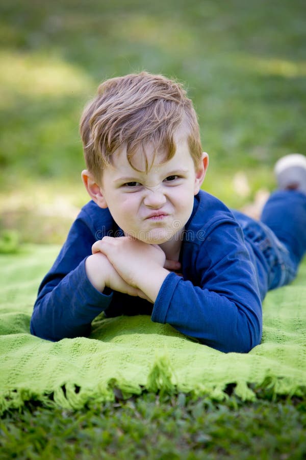 Young Boy Pulling Grumpy Face while Laying on Blanket Outdoors Stock ...