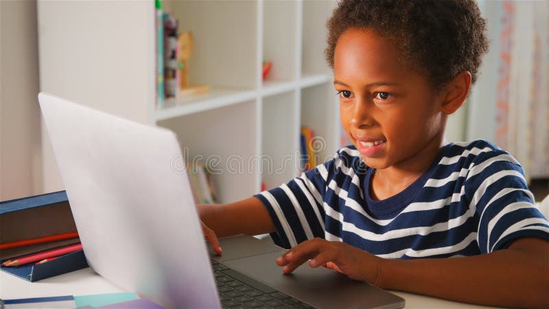 Young Boy Sitting at Desk in Bedroom at Home Using Laptop Computer ...
