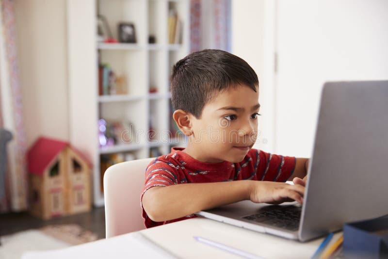 Young Boy Sitting at Desk in Bedroom Using Laptop To Do Homework Stock ...