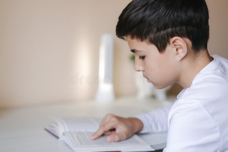 Young Boy Sitting at Desk and Read the Book. Study at Home during ...