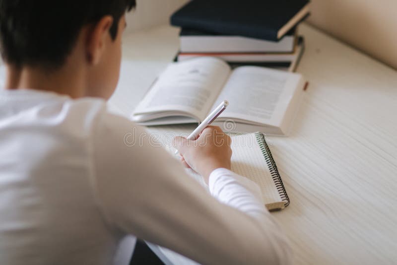 Young Boy Sitting at Desk Read the Book and Write Down in Notebook ...