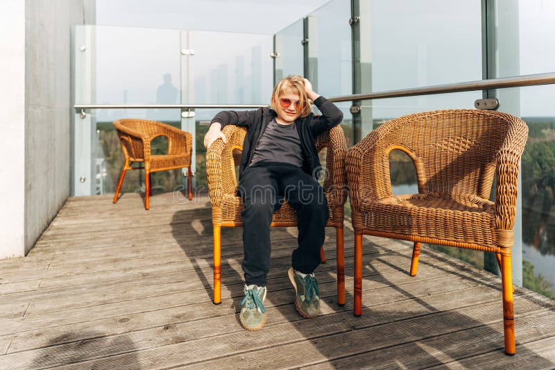 Young Boy Sitting on a Rooftop Terrace, Enjoying the Sunlight and Urban ...
