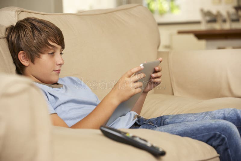 Young Boy Sitting on Sofa at Home Using Tablet Computer Stock Image ...