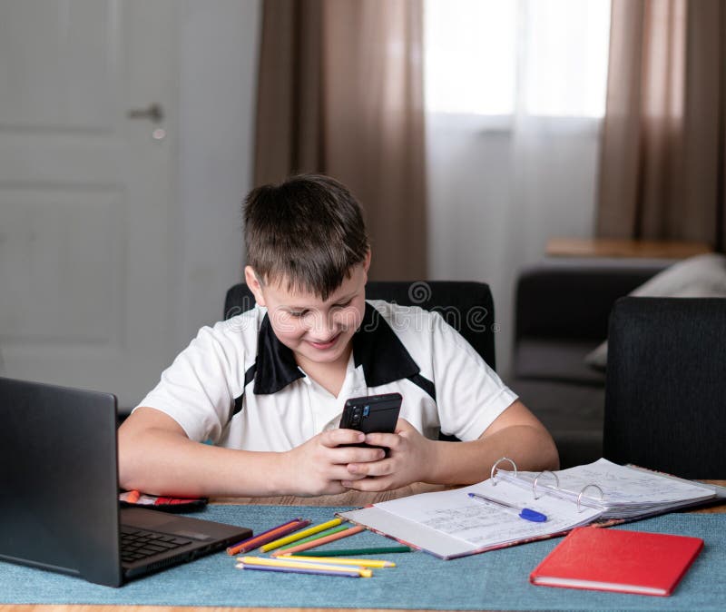 Young Boy Smiling Using His Smartphone while Doing Homework Stock Photo ...